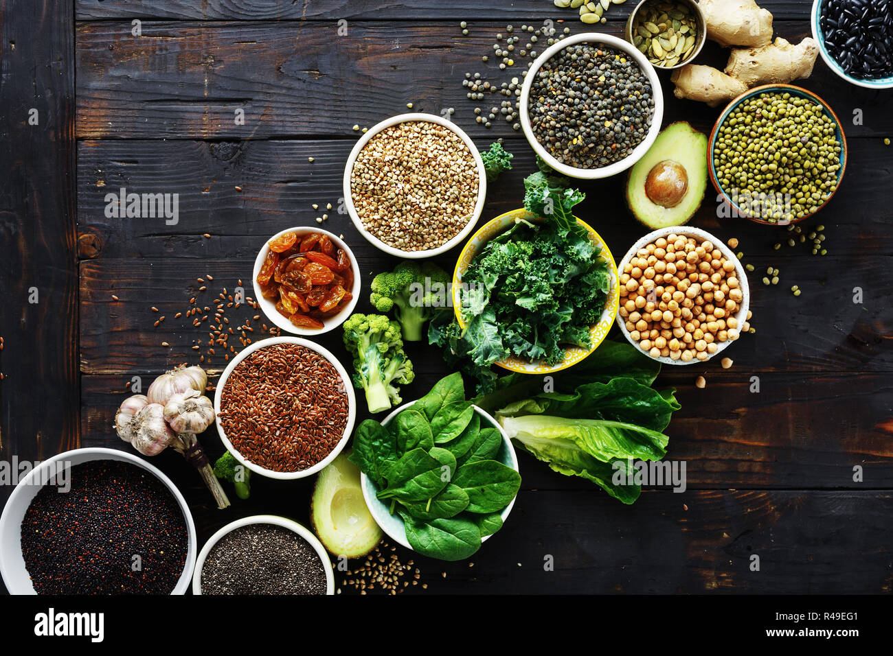 Set superfoods on dark wooden table. Leaves, cereals and seeds top view ...