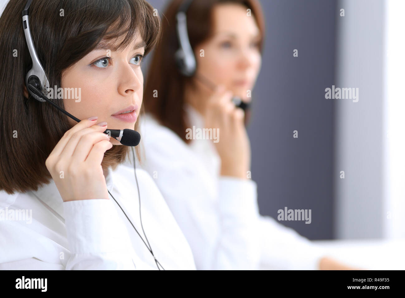 Call center. Group of operators at work. Focus on young brunette woman ...
