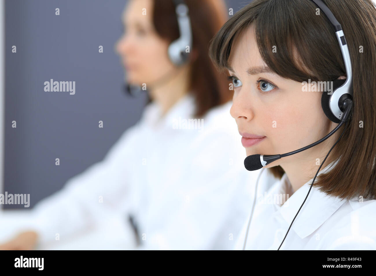 Call center. Group of operators at work. Focus on young brunette woman. Business concept Stock ...