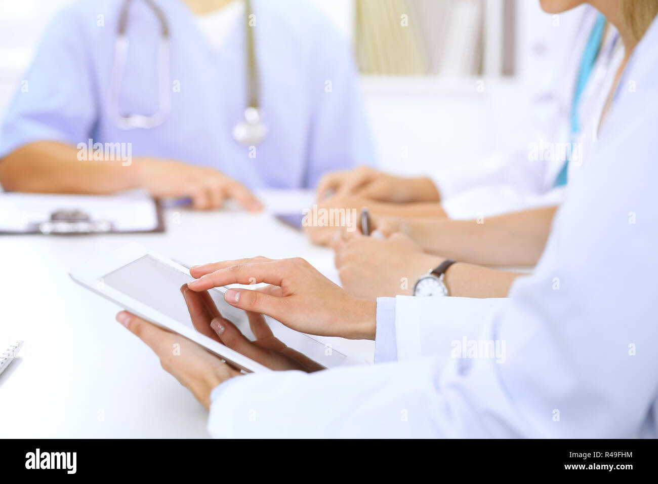 Doctor using tablet computer at medical meeting, closeup. Group of ...
