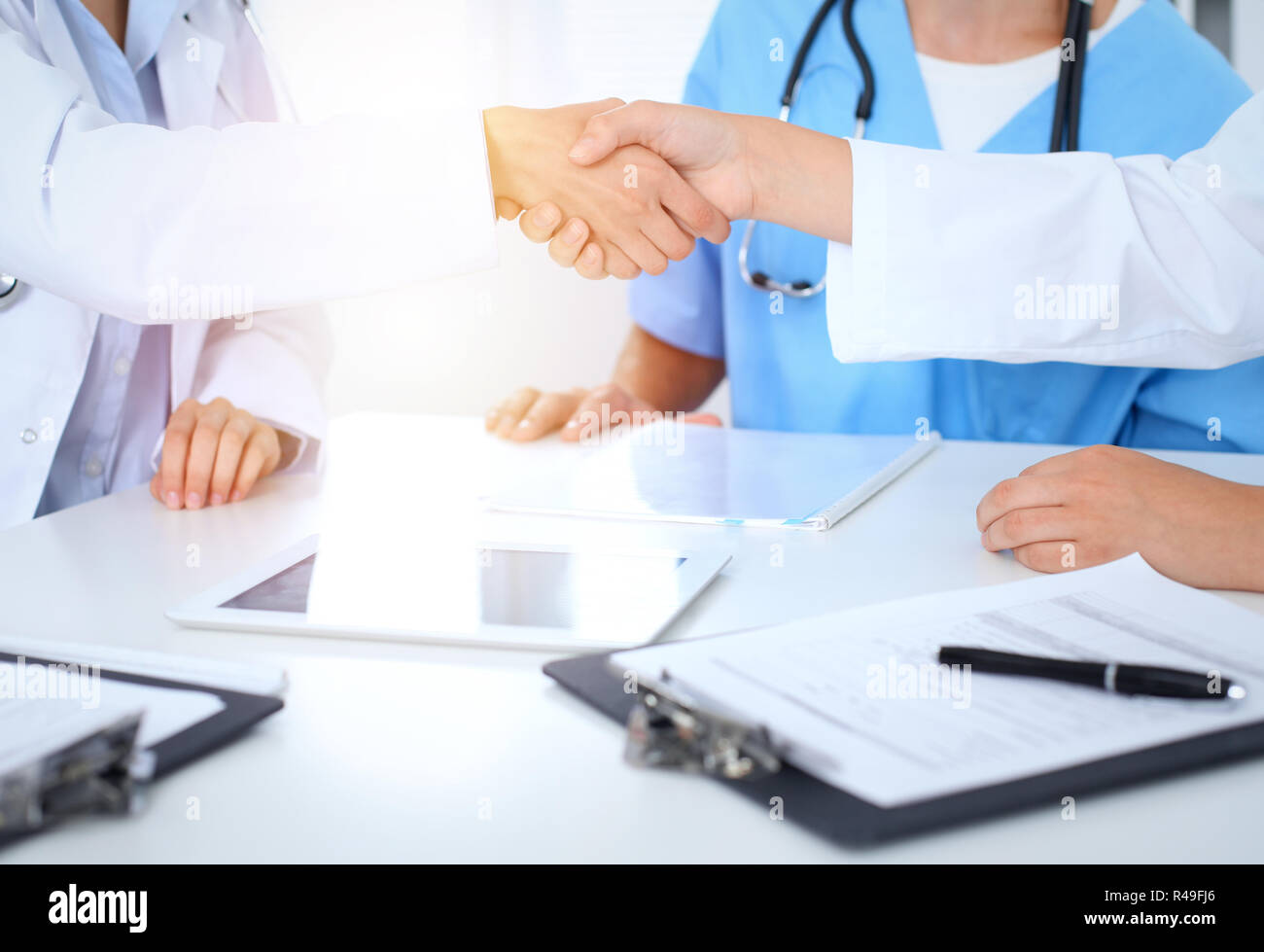 Two doctors shaking hands to each other at meeting. Teamwork and ...
