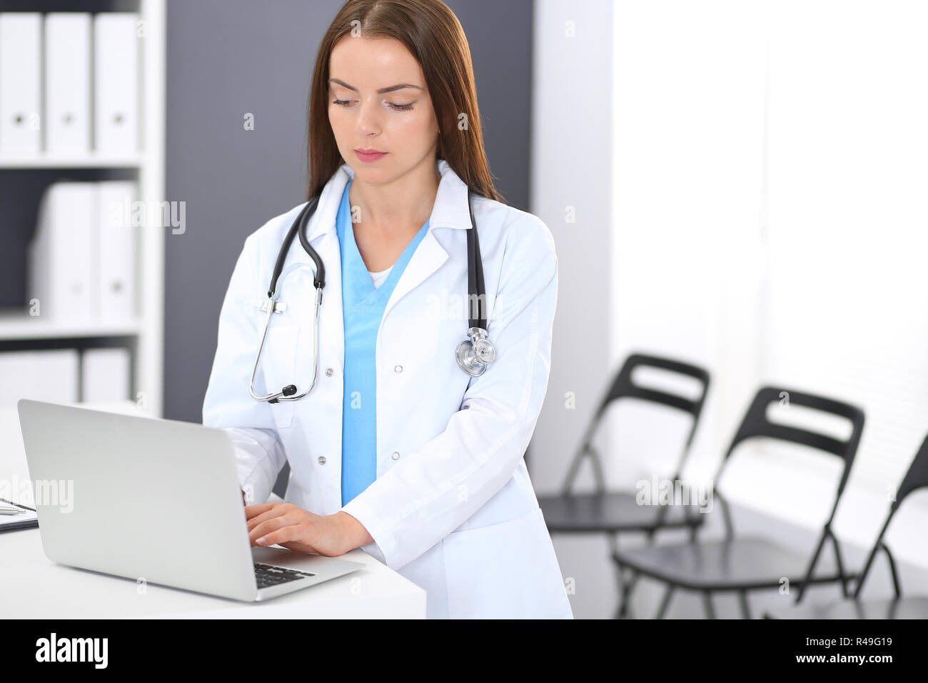 Doctor woman at work. Portrait of female physician using laptop ...