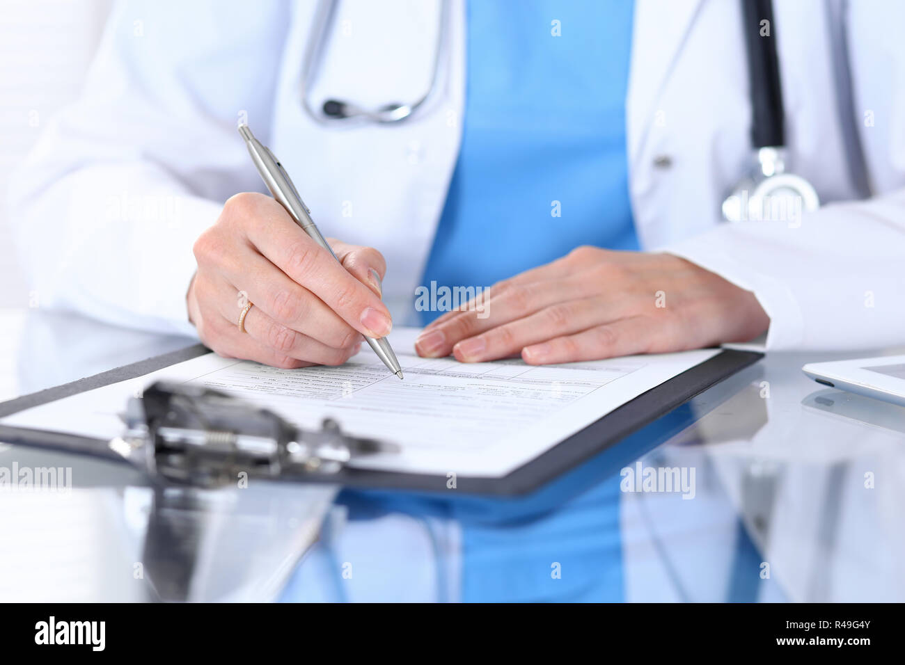Female doctor filling up medical form on a clipboard, closeup ...