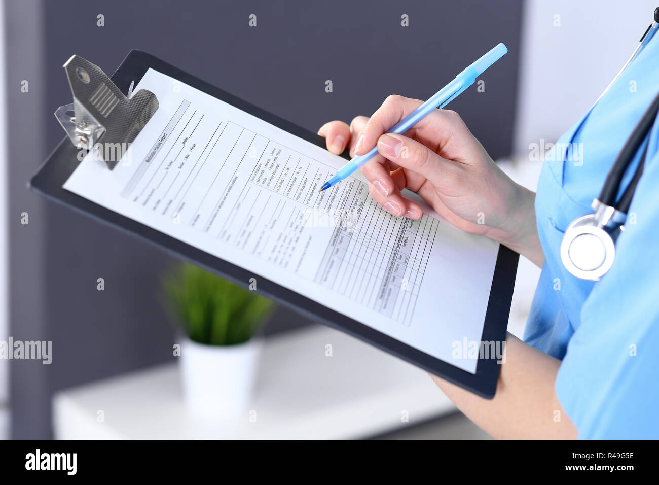 Female doctor filling up medical form on a clipboard, closeup ...