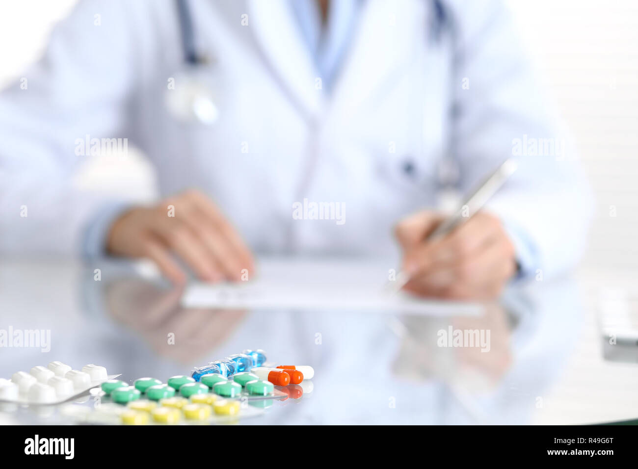 Medicine pills closeup with doctor writing prescription form back in ...