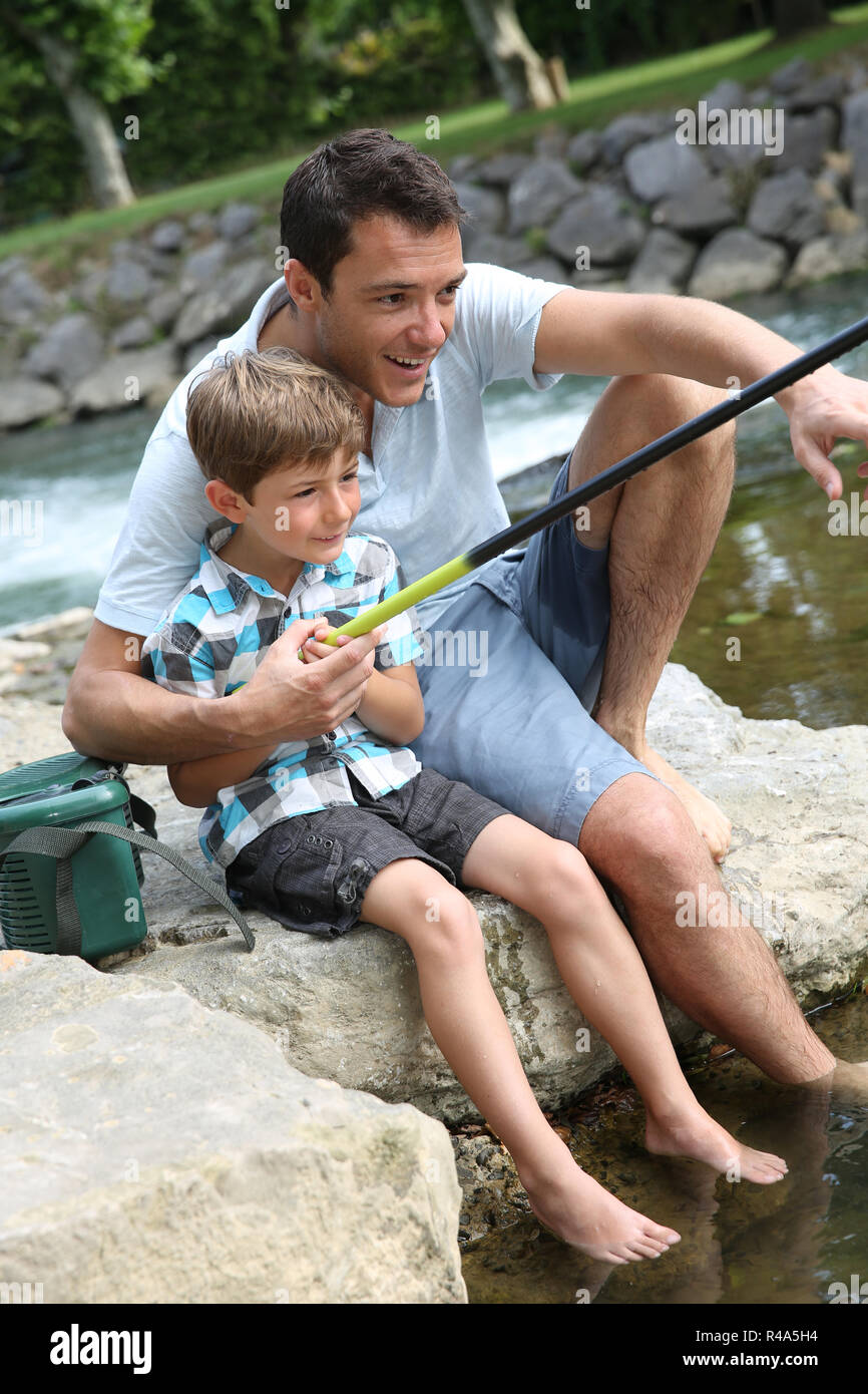 Father teaching son how to fish in river Stock Photo - Alamy