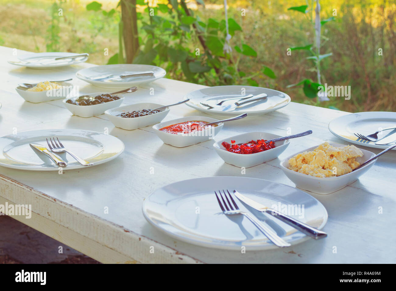Outdoor white vintage table set for breakfast with empty plates ready ...