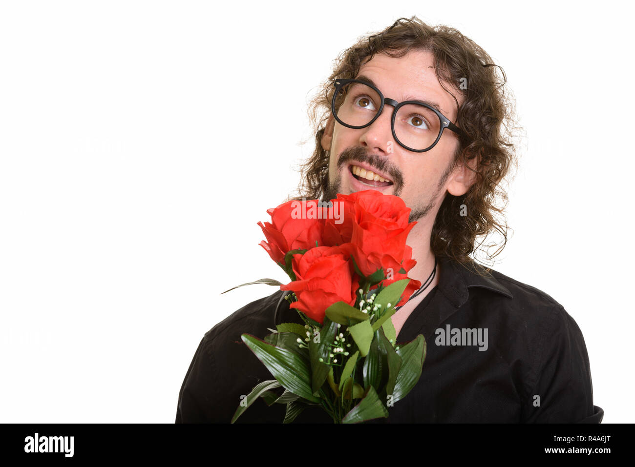 Happy handsome Caucasian man holding red roses while thinking re Stock ...