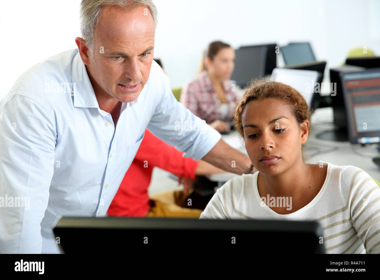 Teacher with student working on desktop computer Stock Photo - Alamy