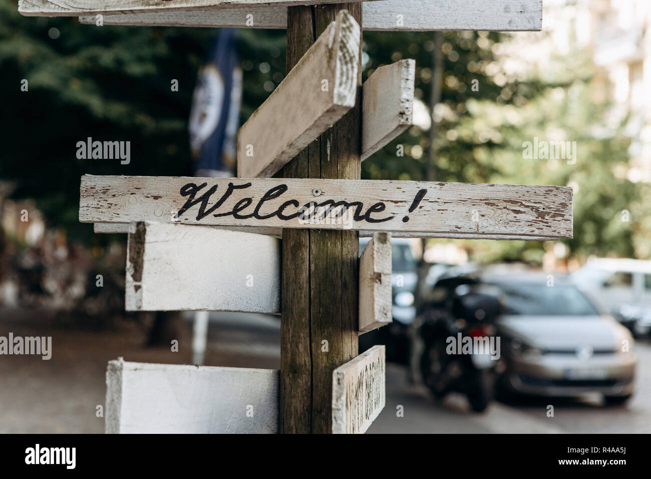 Wooden sign on the street - Welcome. Blurred street in the background ...