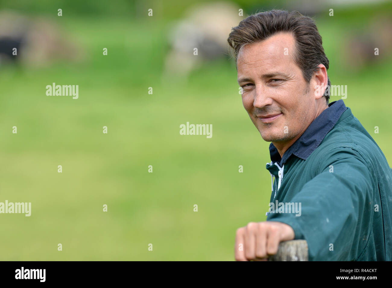 Smiling farmer standing in country field Stock Photo - Alamy