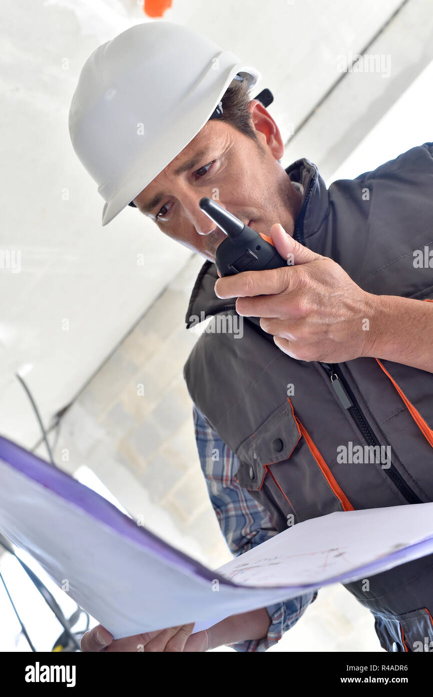 Construction worker checking blueprint on site Stock Photo - Alamy