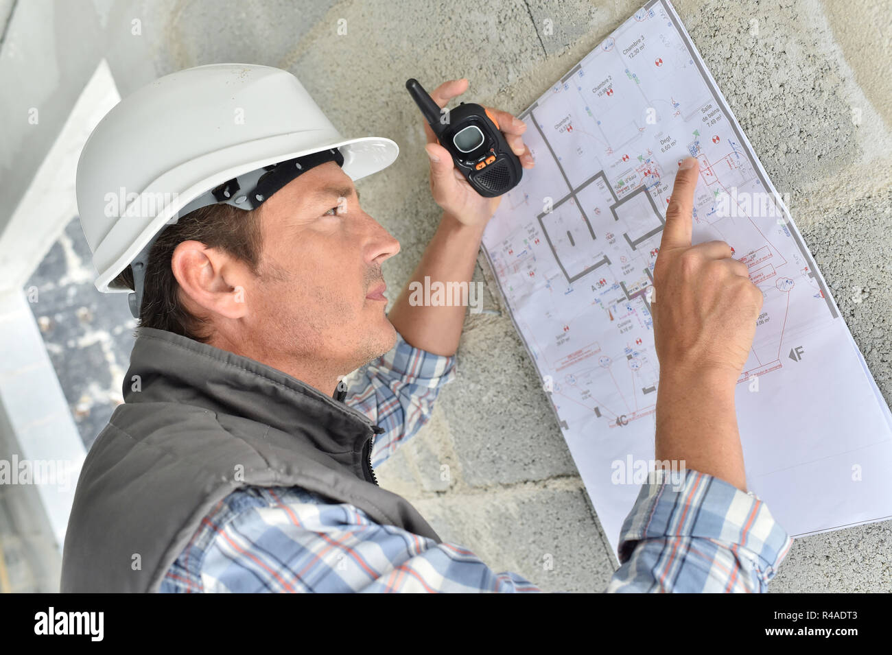 Engineer on building site checking blueprint Stock Photo - Alamy