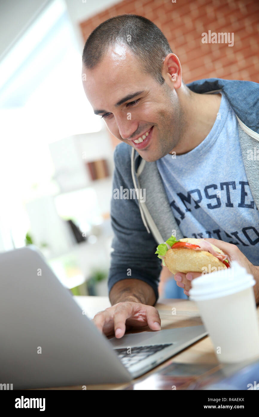 Student eating sandwich in front of laptop Stock Photo - Alamy