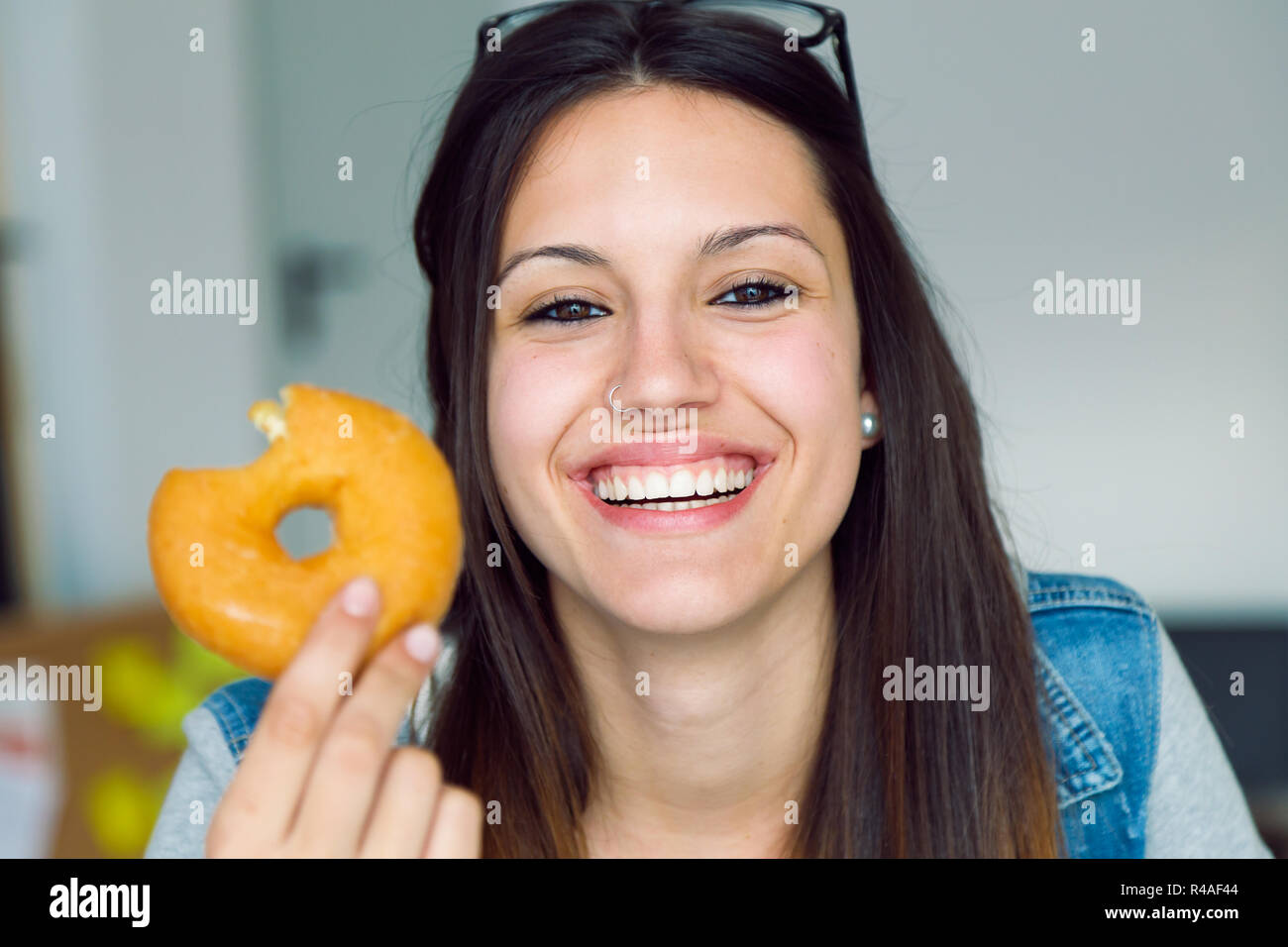 Beautiful young woman eating donuts at home Stock Photo - Alamy