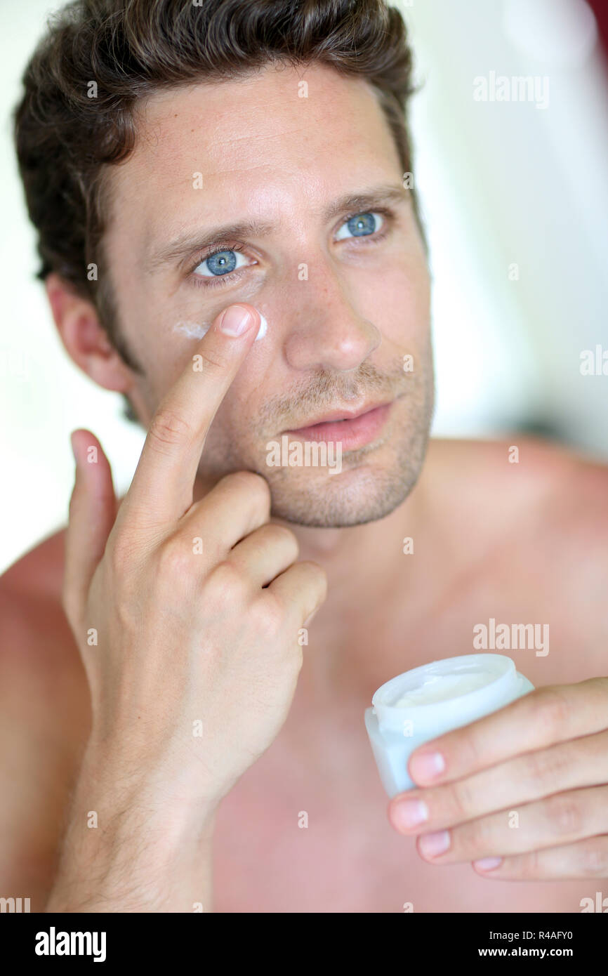 Handsome man applying moisturizing cream Stock Photo - Alamy