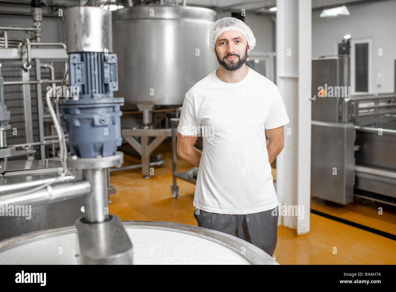 Portrait of a handsome worker in uniform near the stainless tank full ...
