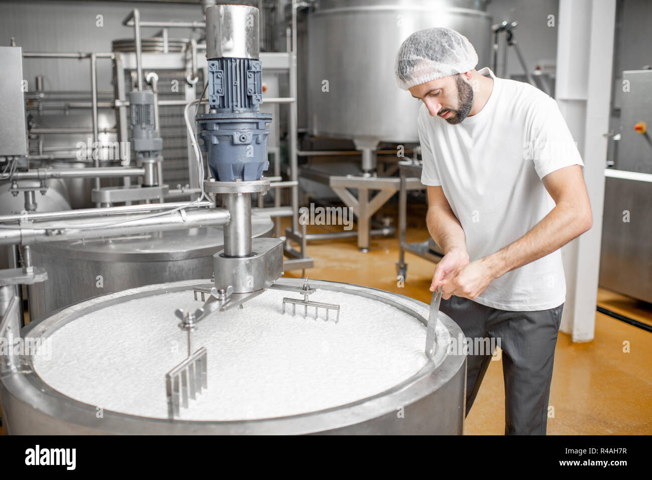 Man mixing milk in the stainless tank during the fermentation process ...