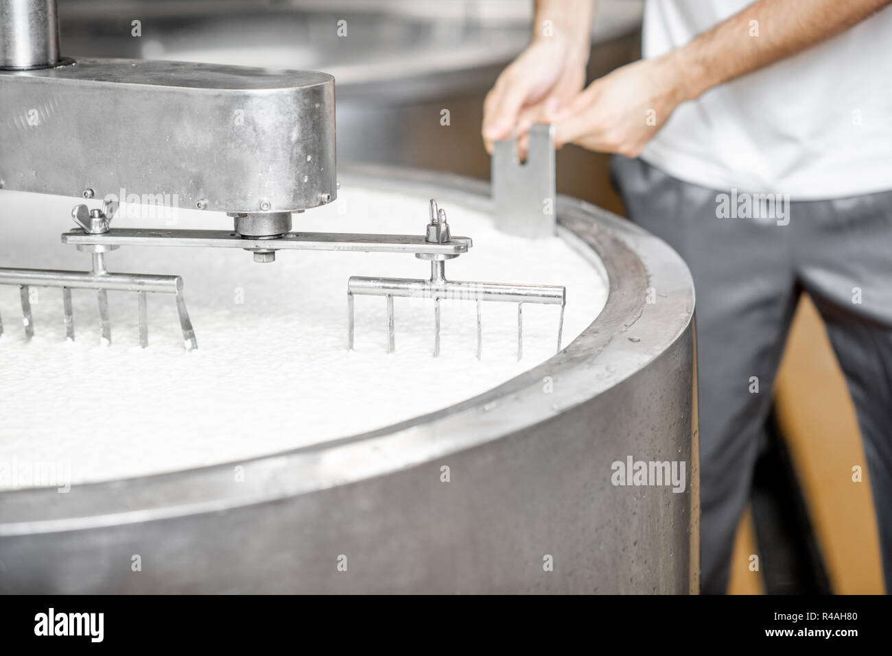 Man mixing milk in the stainless tank during the fermentation process ...
