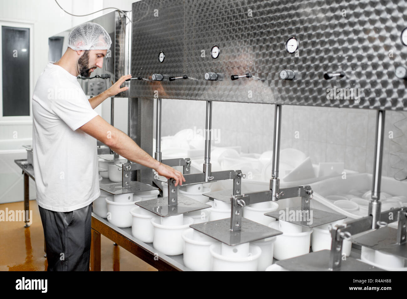 Worker operating press machine pressing cheese at the manufacturing ...