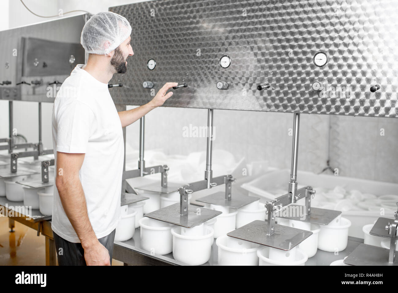 Worker operating press machine pressing cheese at the manufacturing ...