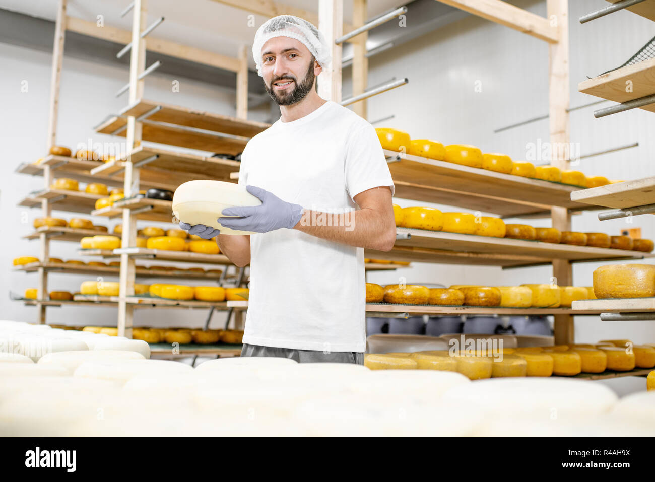 Man checking the quality of the fresh cheese wheels after the waxing ...