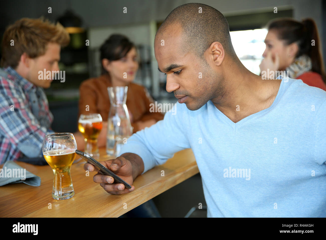 Man sitting at snack bar table checking messages Stock Photo - Alamy