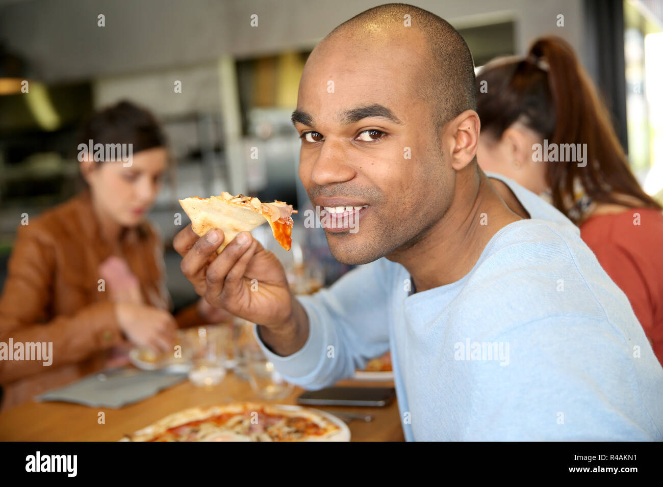 Young man having eating pizza slice Stock Photo - Alamy