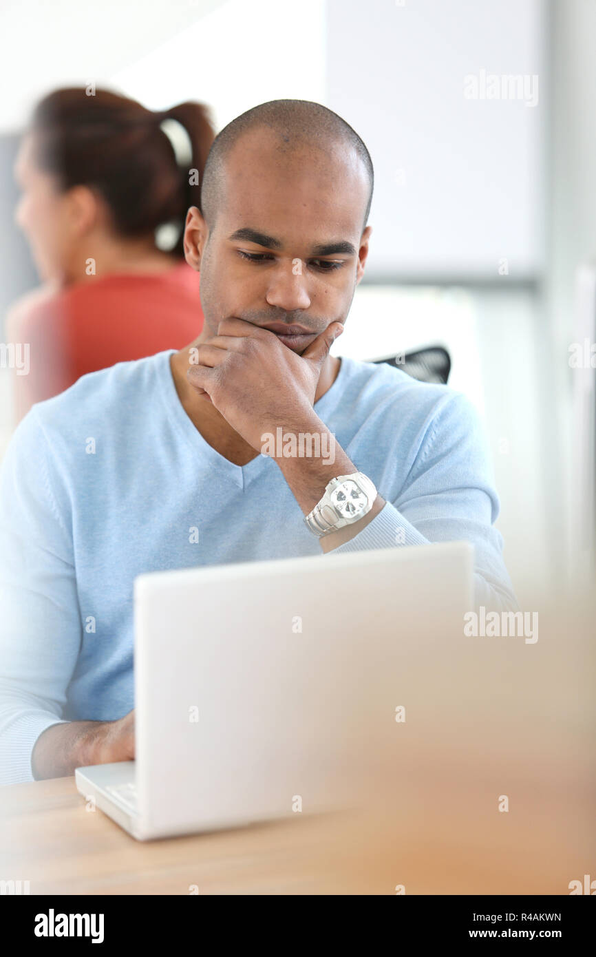 Young man in class working on laptop computer Stock Photo - Alamy