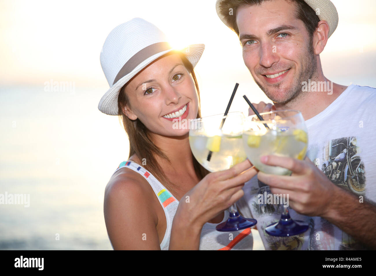 Couple enjoying cocktail drinks at sunset time Stock Photo - Alamy