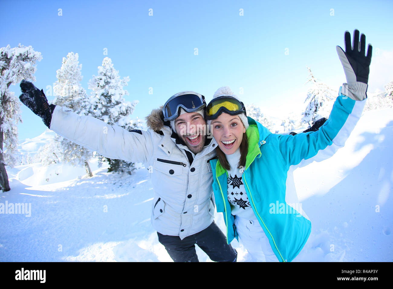 Cheerful couple of skiers lifting arms up Stock Photo - Alamy