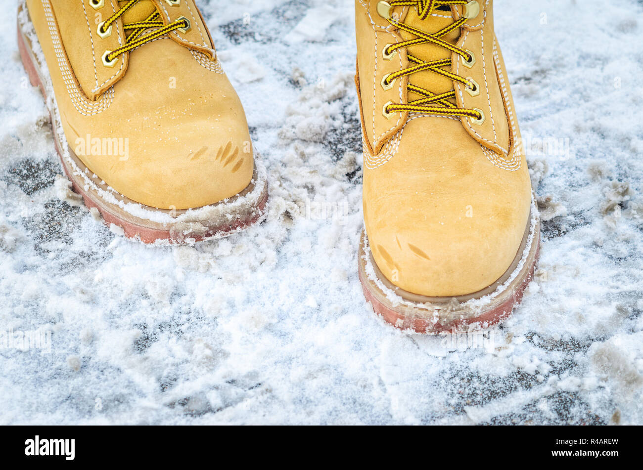 Yellow working boots from nubuck in the snow footpath. Winter footwear ...
