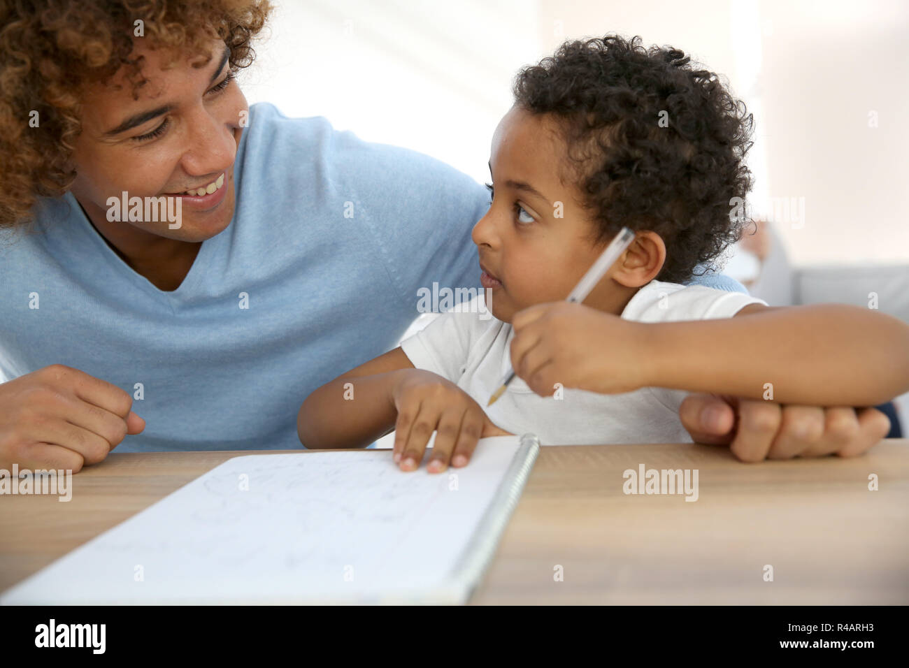 Daddy and son drawing on notebook at home Stock Photo - Alamy