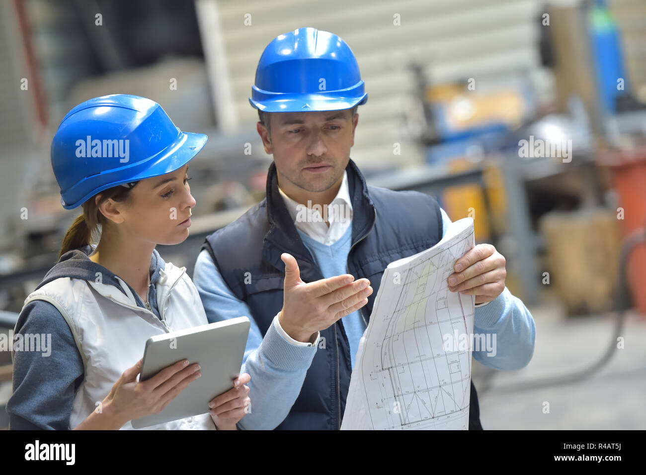 Engineers in mechanical factory reading instructions Stock Photo - Alamy