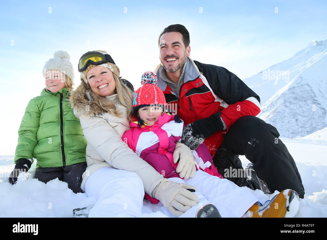 Cheerful family sitting in snow Stock Photo - Alamy