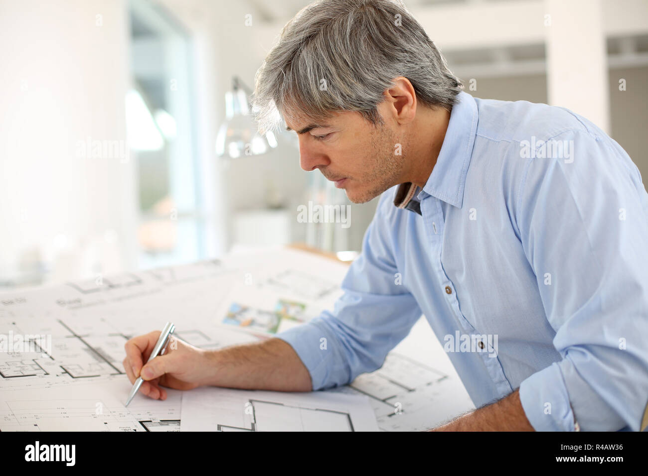 Architect working on construction blueprint in office Stock Photo - Alamy