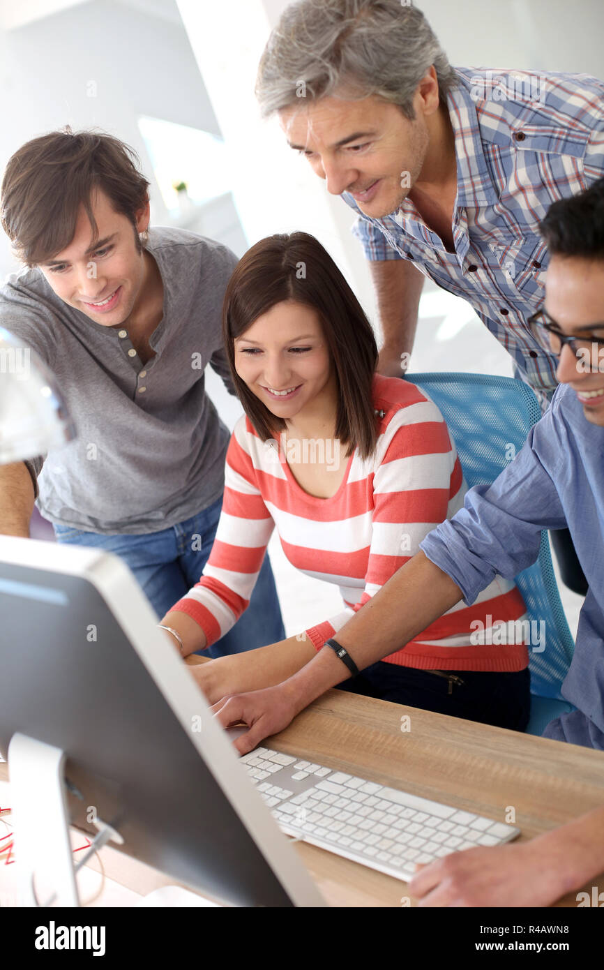 Teacher with students working on desktop Stock Photo - Alamy