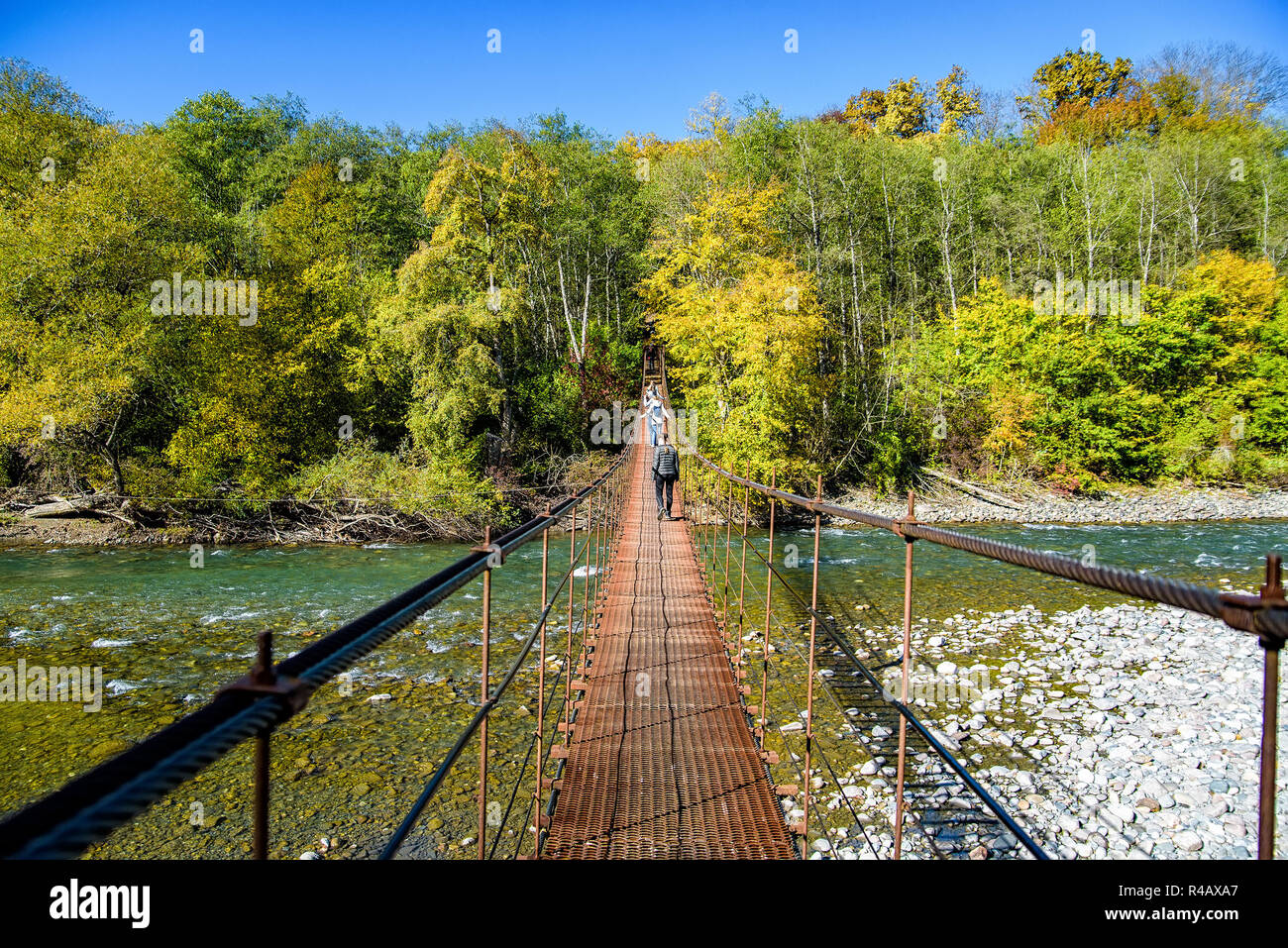 Hikers on suspension foot bridge over mountain river Stock Photo - Alamy