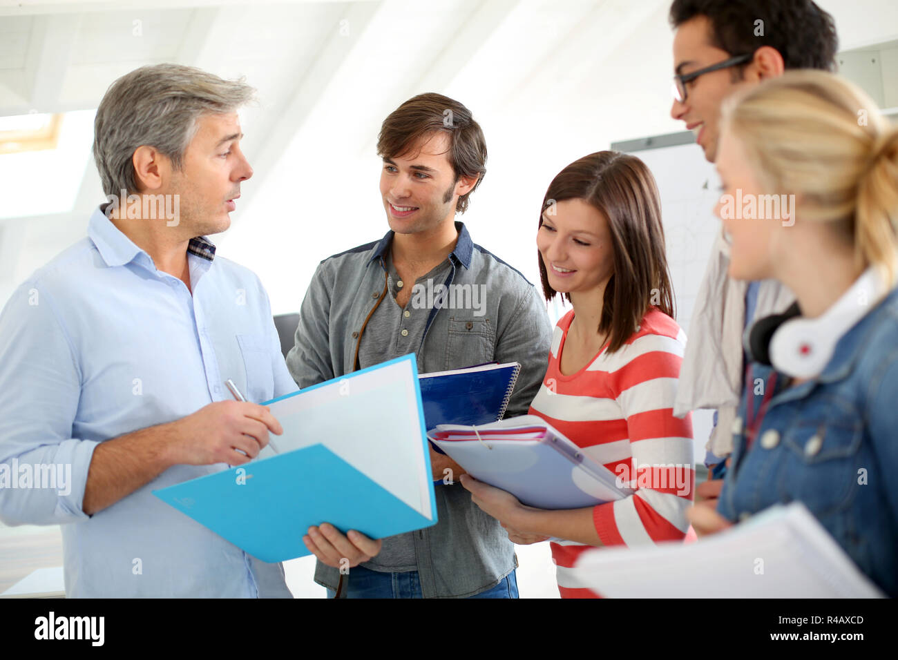 Students in school hallway asking questions to teacher Stock Photo - Alamy