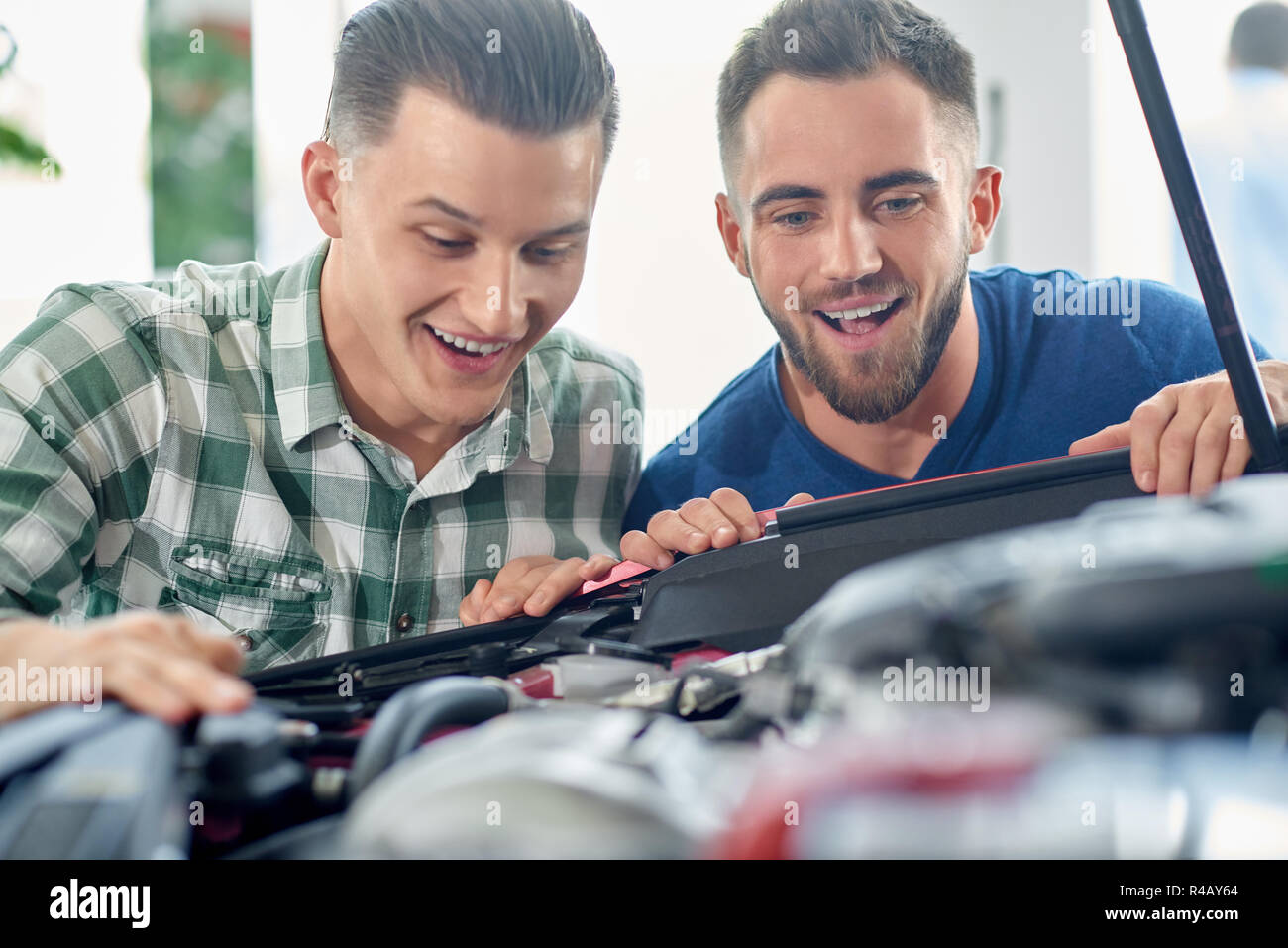 Portrait of two attractive men looking at car's engine and fixing it ...