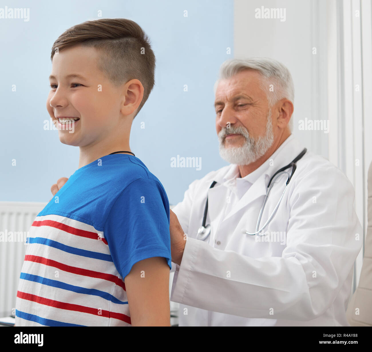 Physician looking at patient's back and examining posture of little boy ...