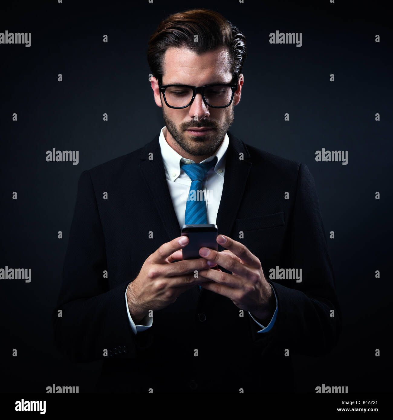 Handsome stylish man in elegant black suit using mobile phone Stock ...