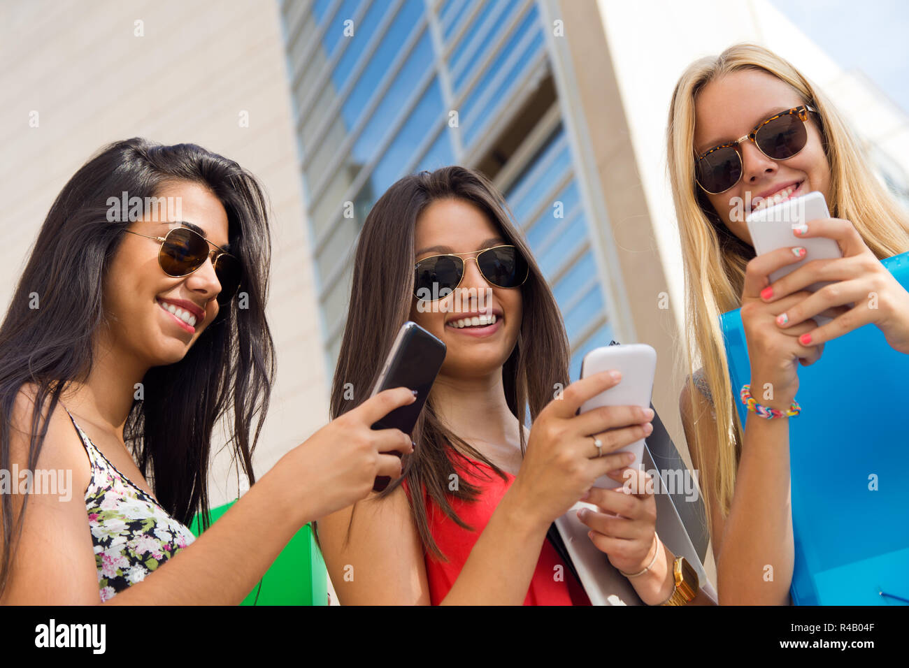 Three girls chatting with their smartphones at the campus Stock Photo ...
