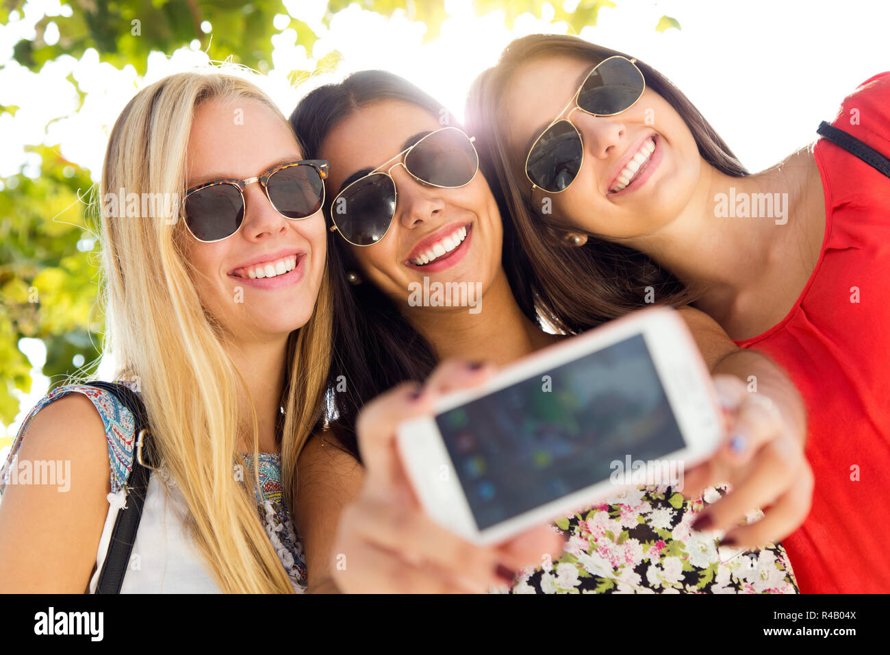 Three friends taking photos with a smartphone Stock Photo - Alamy