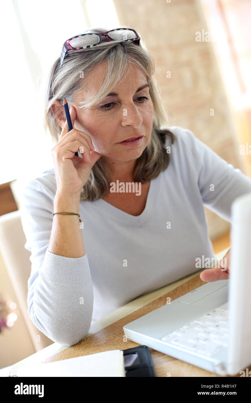 Perplexed senior woman in front of laptop Stock Photo - Alamy