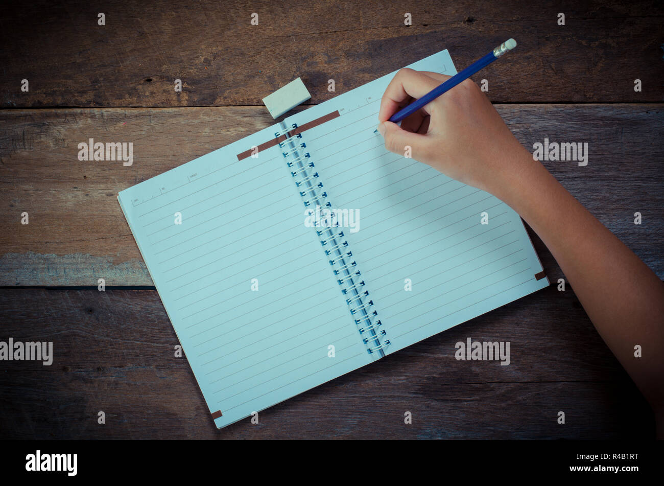 Hand writing in open notebook on table Stock Photo - Alamy