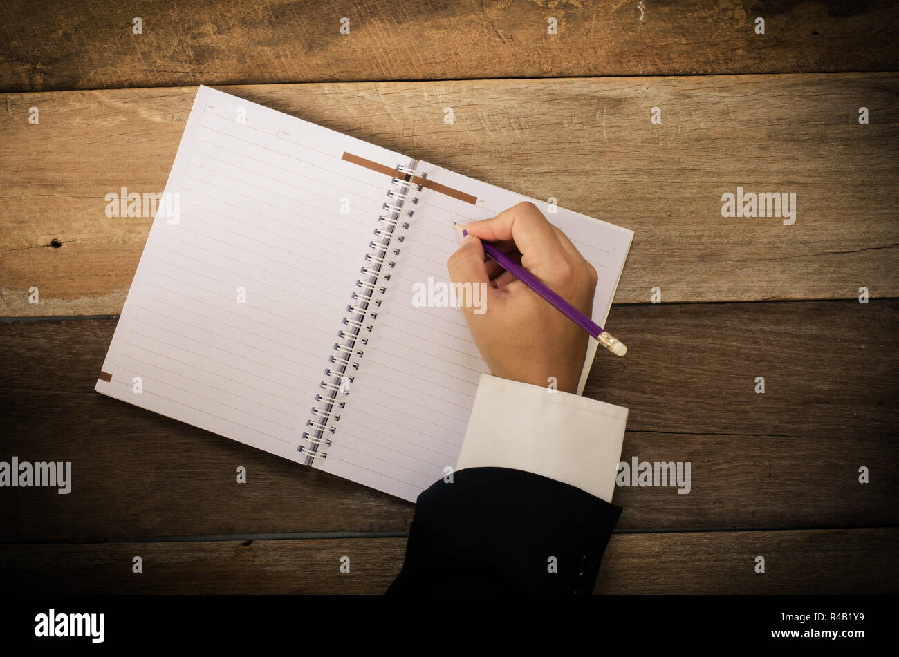 Hand writing in open notebook on table Stock Photo - Alamy