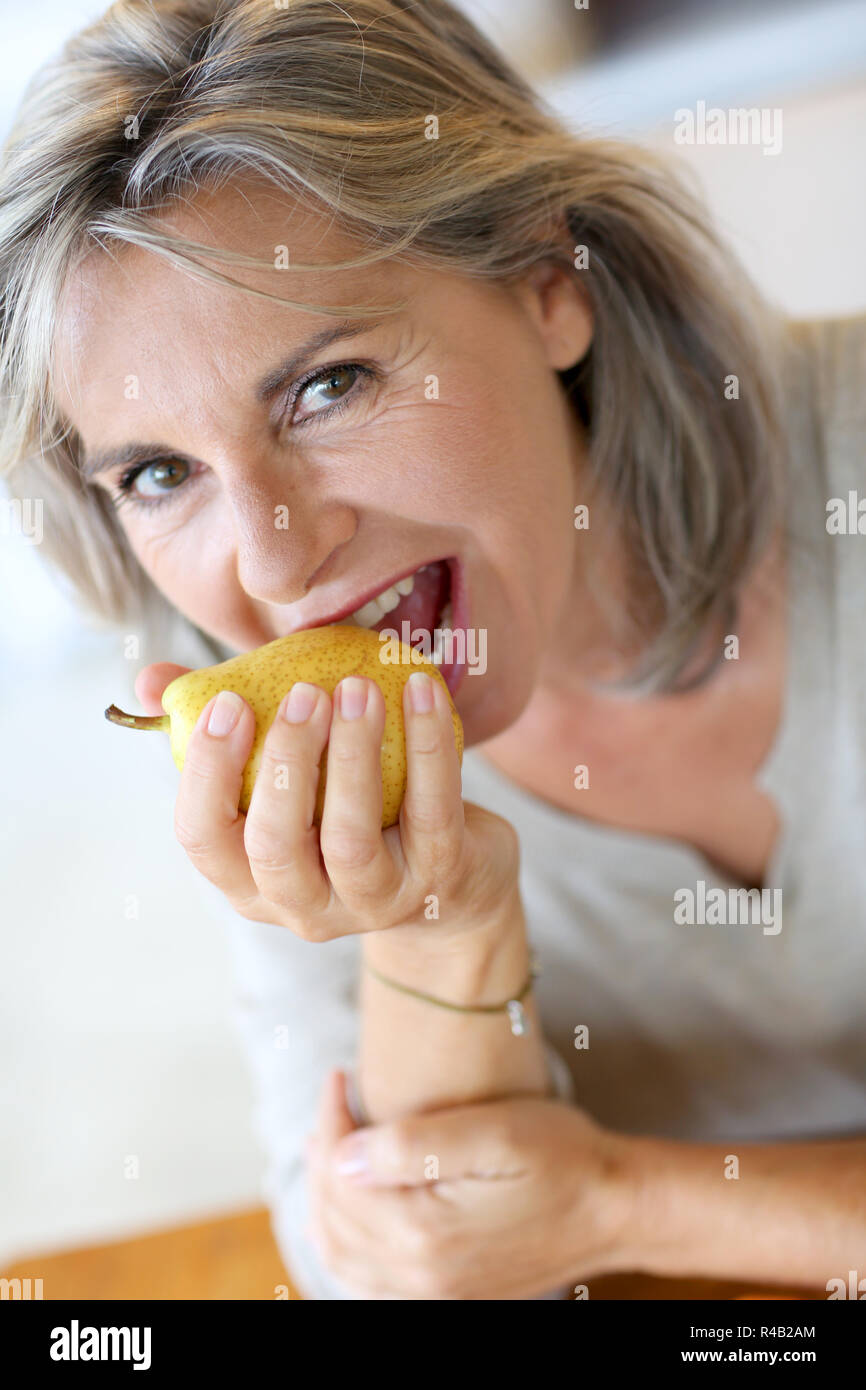Portrait of senior woman eating pear Stock Photo - Alamy