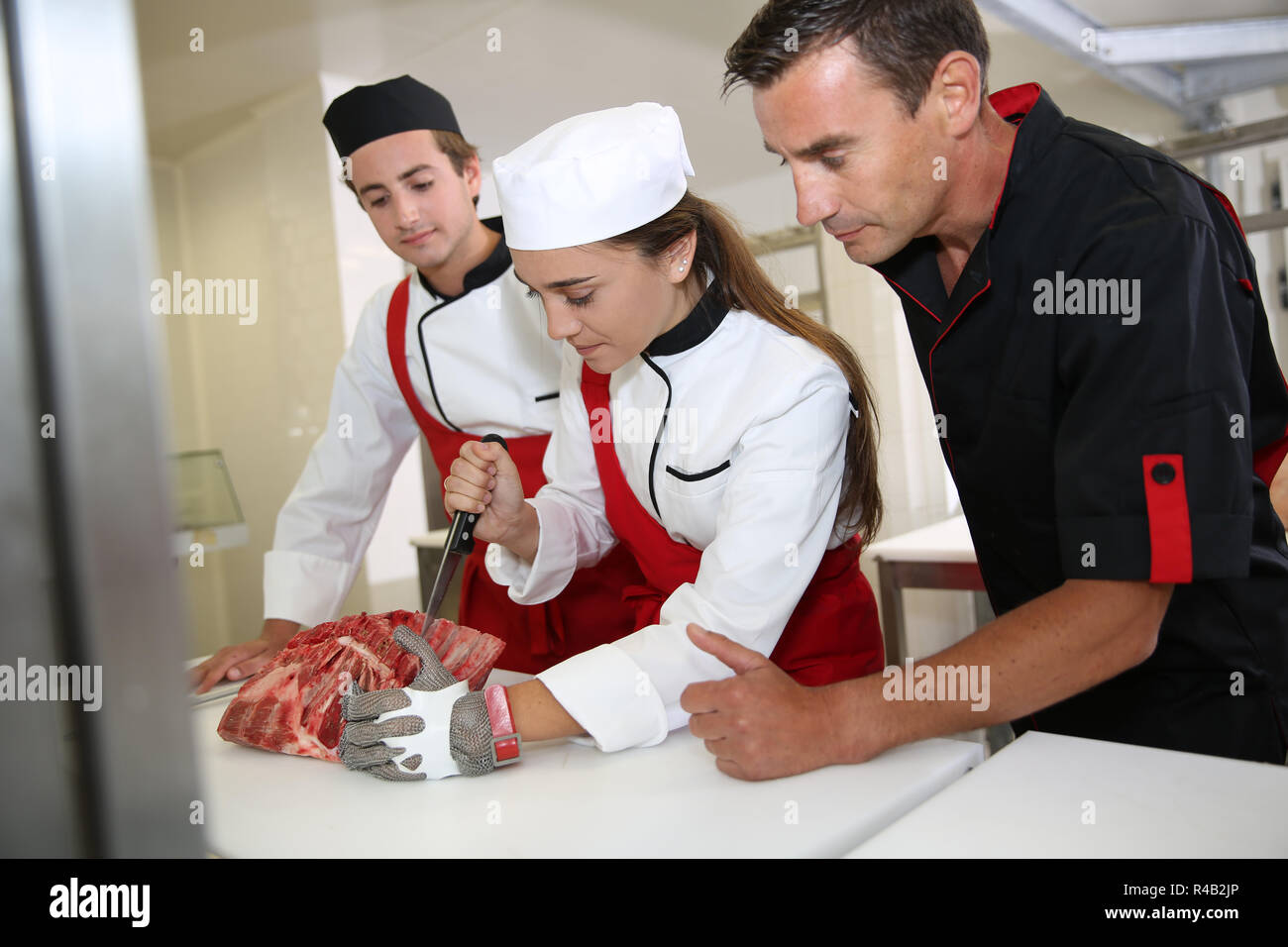Professional butcher teaching students with meat cutting Stock Photo ...
