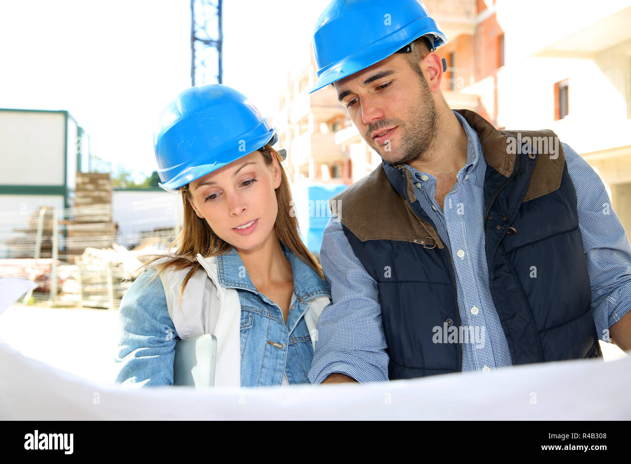 Engineers on building site reading blueprint Stock Photo - Alamy